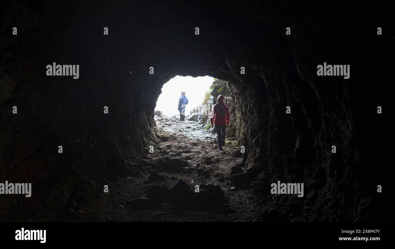 View from cave to tourists. Clip. Rear view of man coming out of cave ...