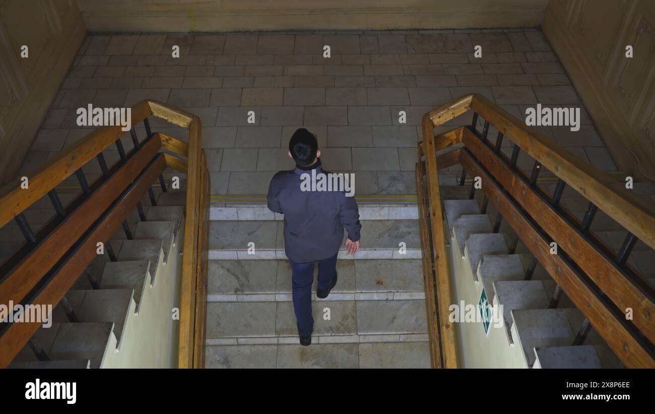 Top view of man walking up stairs of old building. Media. Young man ...