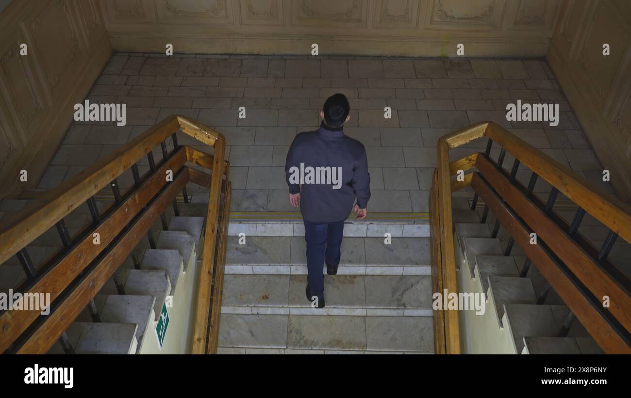 Top view of man walking up stairs of old building. Media. Young man ...