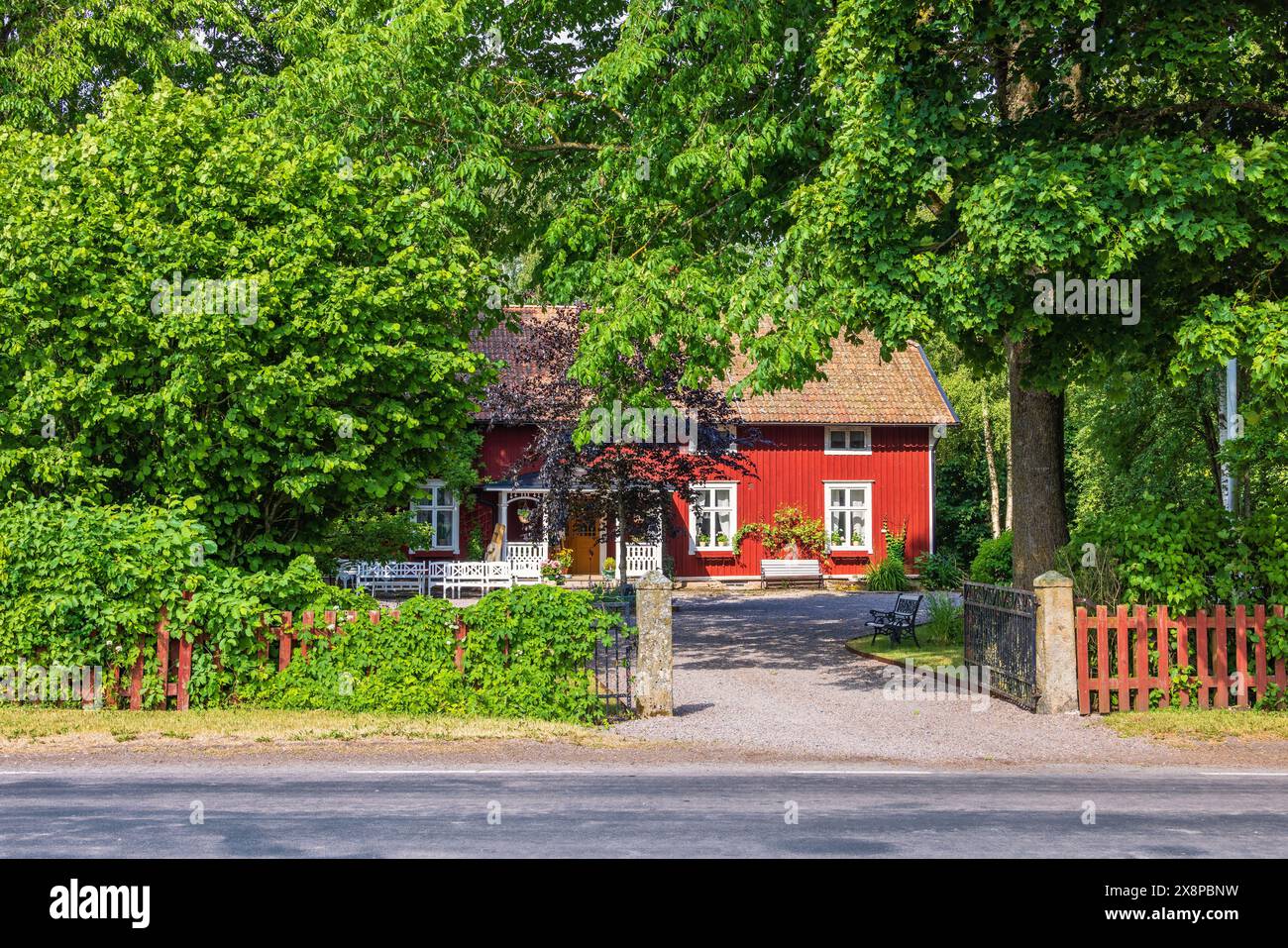 Entrance from a road to a red idyllic house with a wooden fence Stock ...