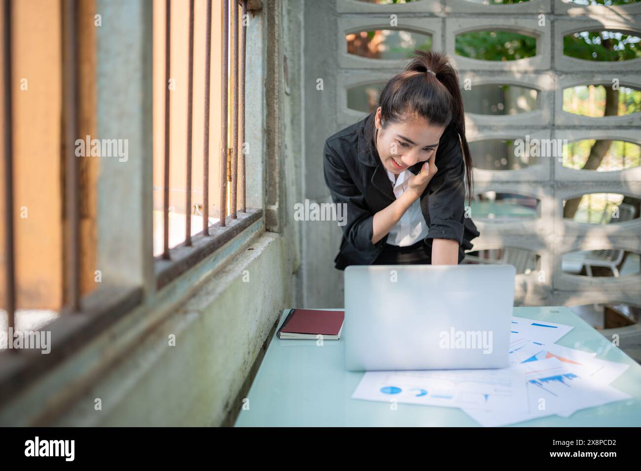 Businesswoman uses smartphone to share internet connection to work on laptop at coffee shop ...