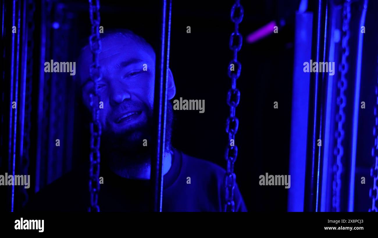 Stylish bearded man dancing by hanging chains in colorful neon light in ...