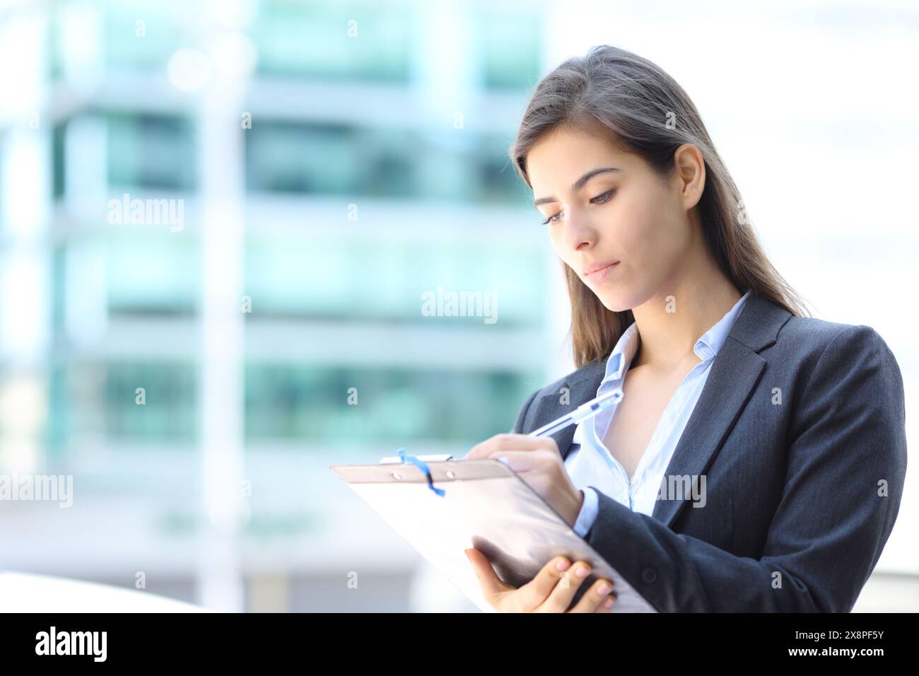 Serious executive filling out form standing in the street Stock Photo ...