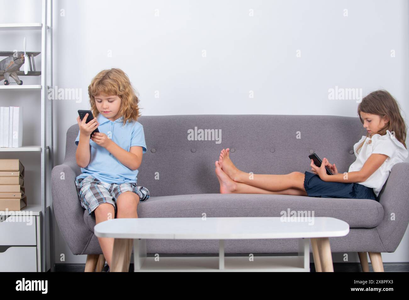 Two children alone with phone at home. Gadget addiction. Mobile addict ...