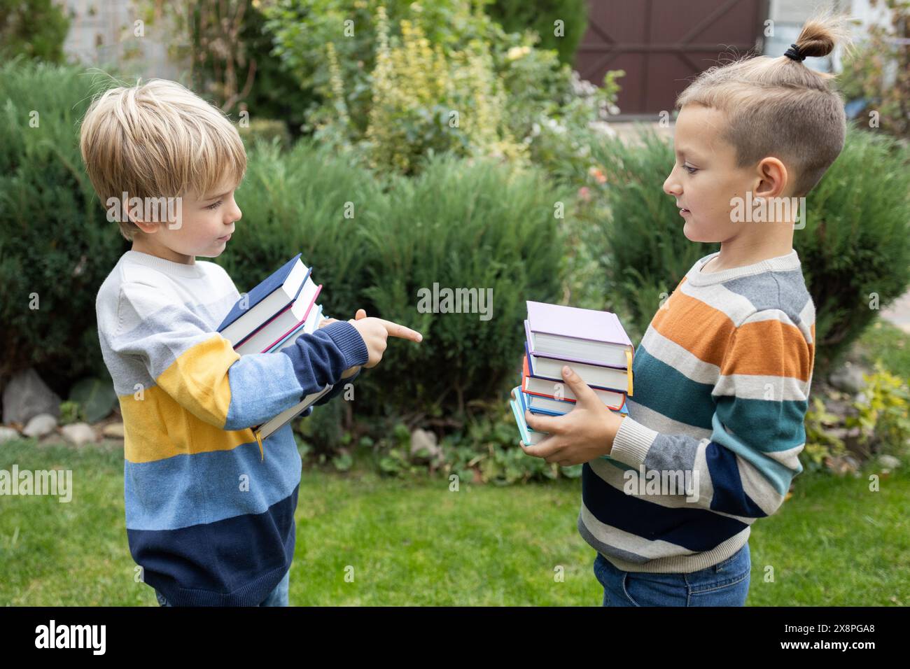 Two brothers or boy friends stand opposite each other hold stacks of ...