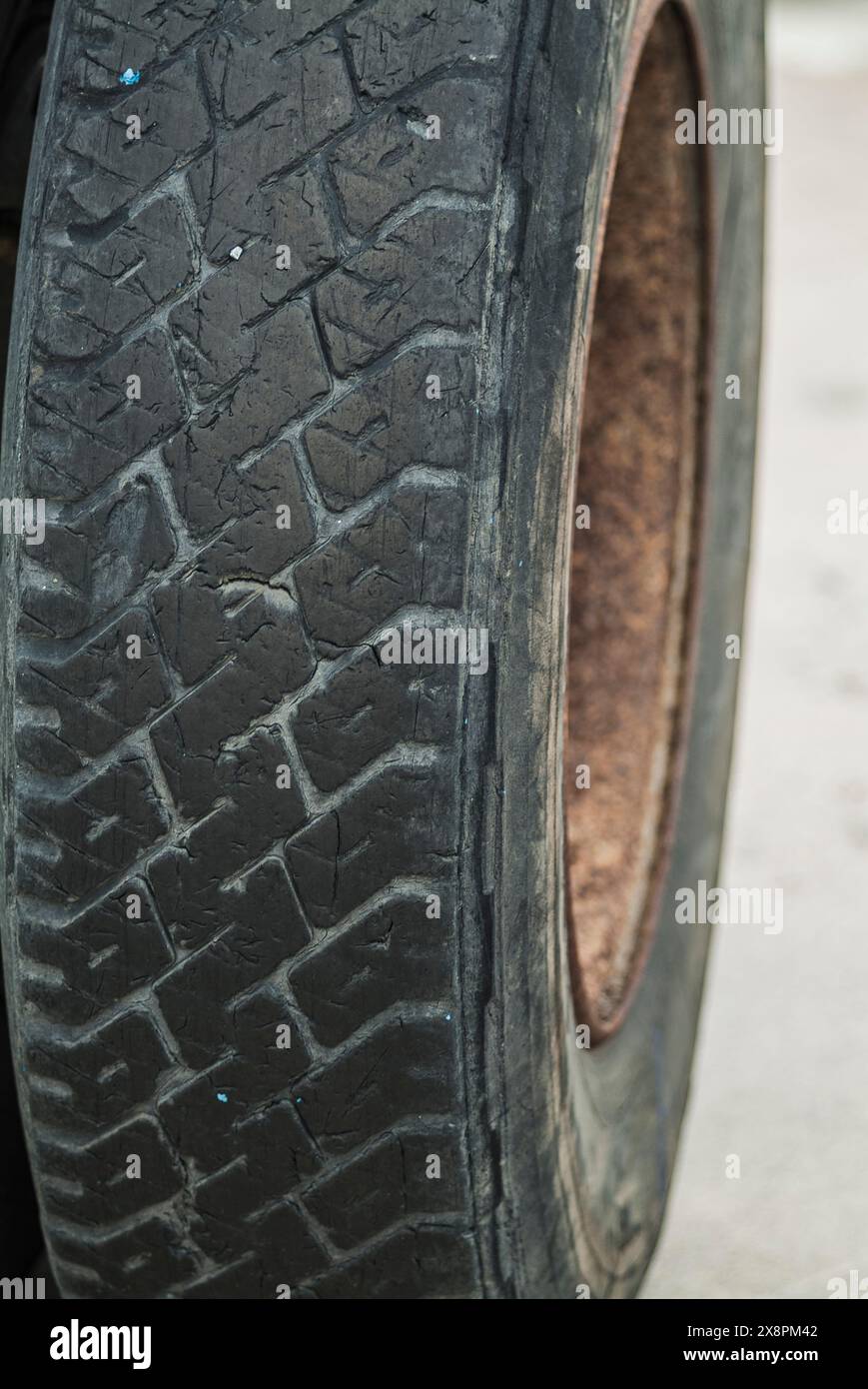 A close-up view of a worn out tire on a vehicle, showing cracks and ...