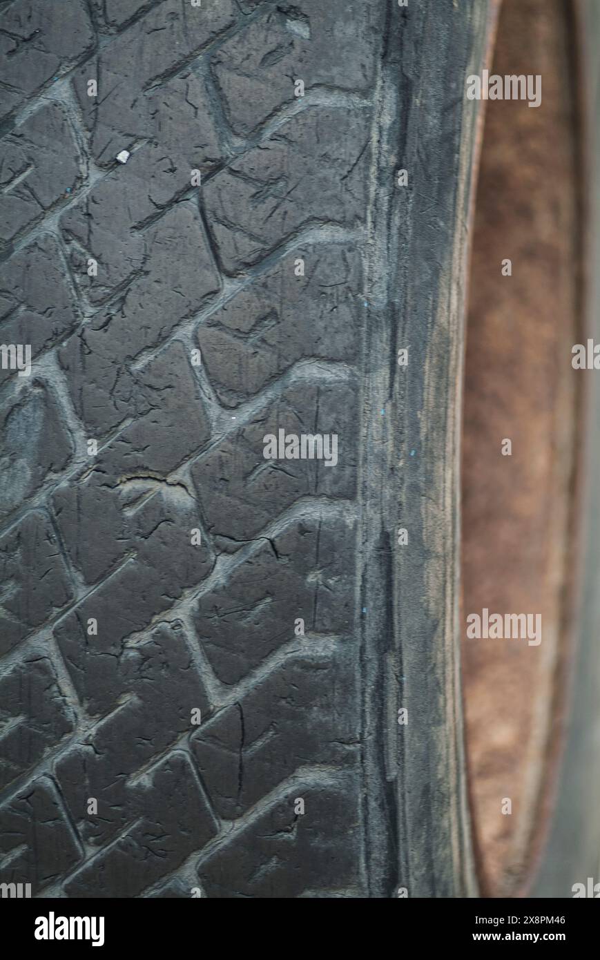 A close-up view of a worn out tire on a vehicle, showing cracks and ...