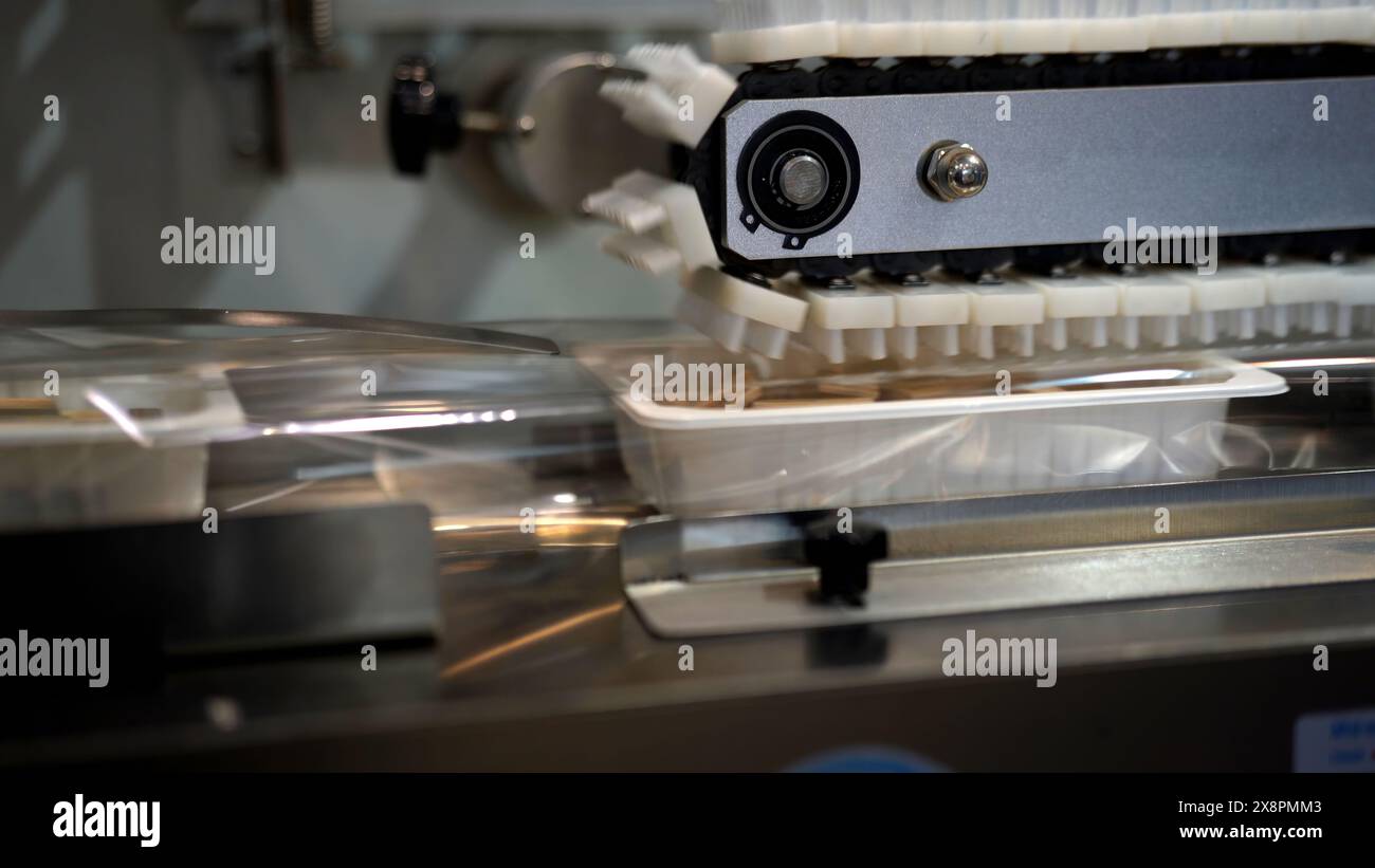 Plastic wrapping machine on production line packing food. Media ...