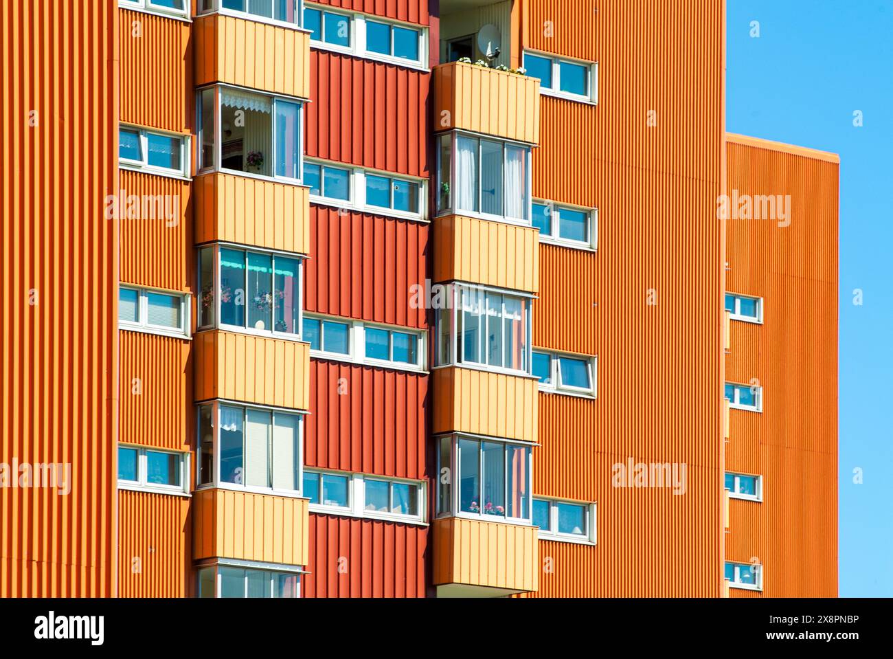 A tall building in shades of orange and red stands prominently, filled ...