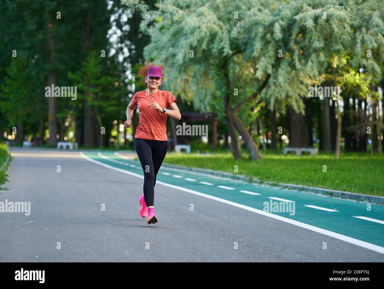 Athletic fit mature woman runner jogging in park on an alley Stock ...