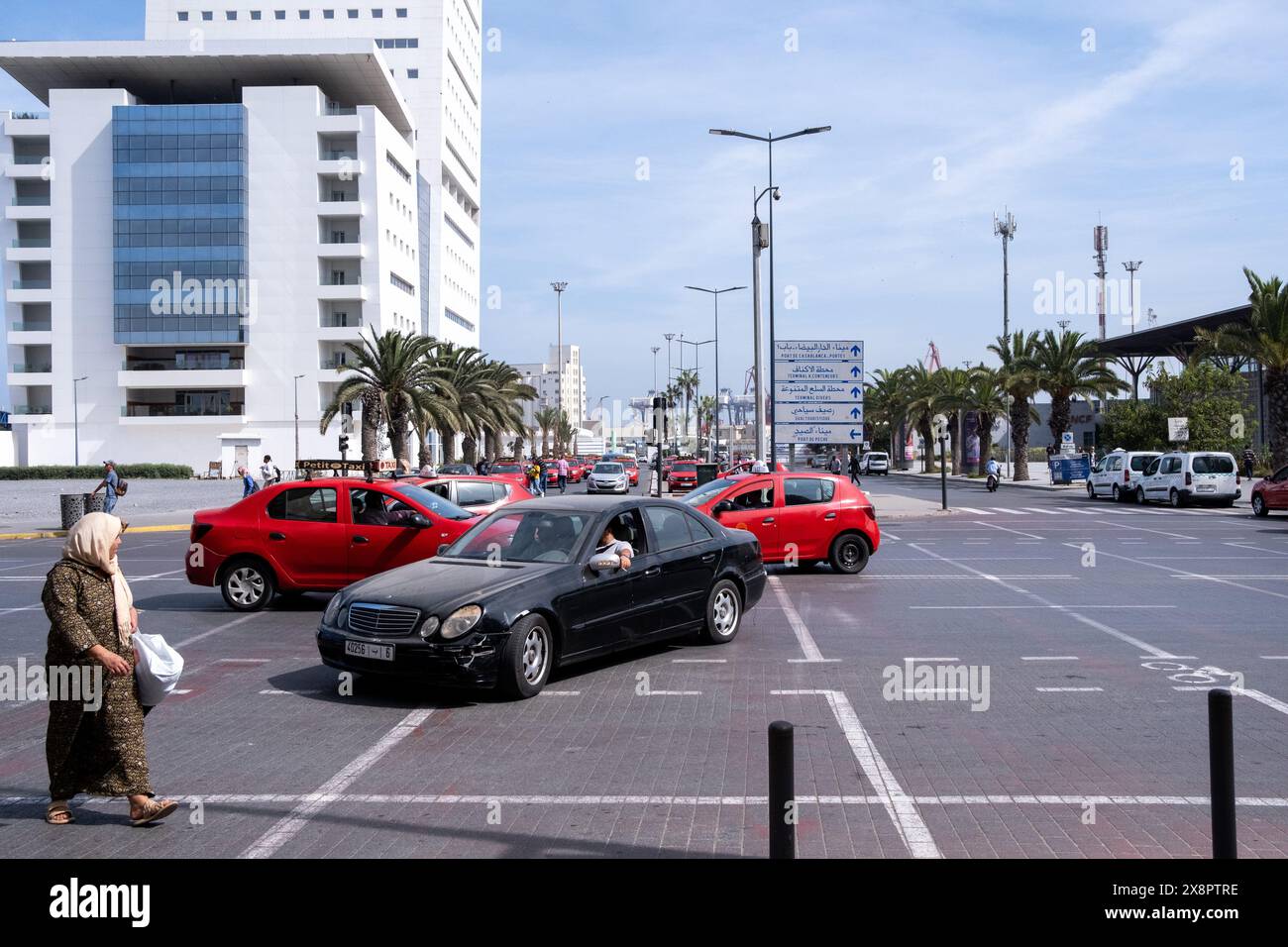 Traffic scene with red and black cars and pedestrians near ANP Tower on ...