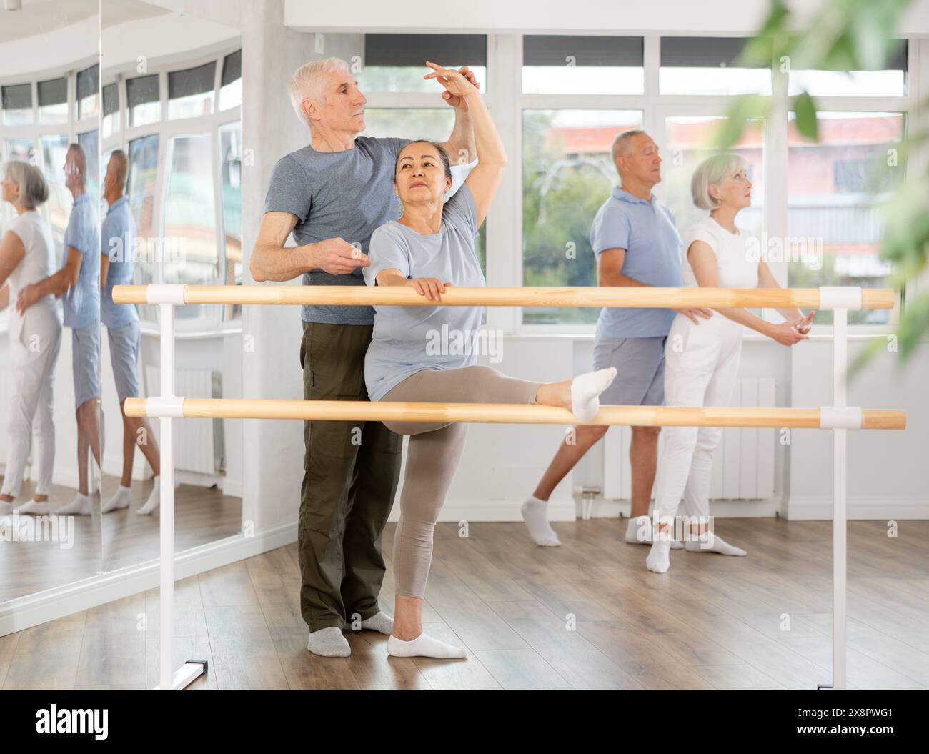 Elderly woman in sportswear, participating in ballet class, mastering ...