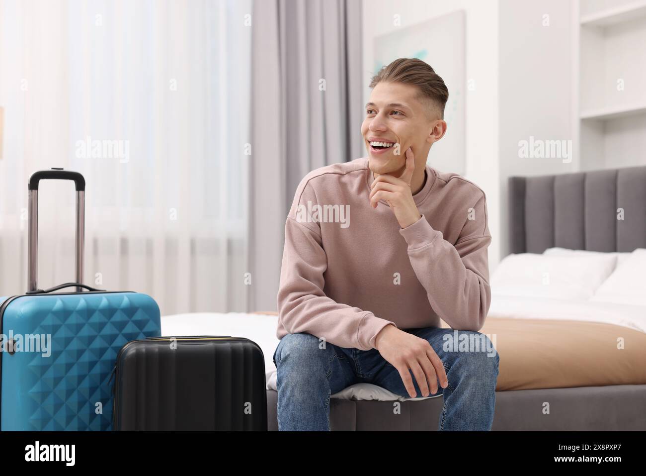 Smiling guest relaxing on bed in stylish hotel room Stock Photo - Alamy