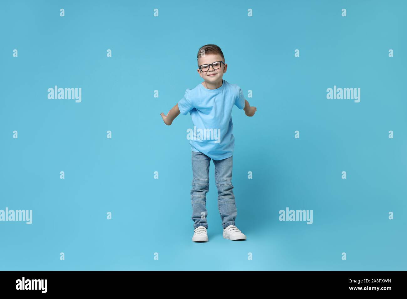 Happy little boy dancing on light blue background Stock Photo - Alamy