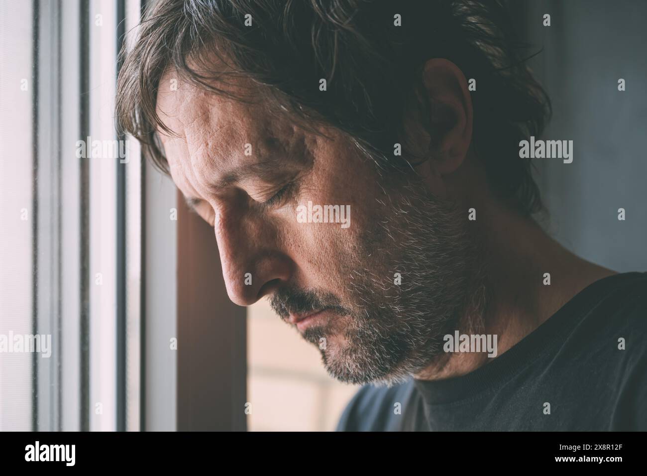 Downhearted man with eyes closed leaning his head close to the ...