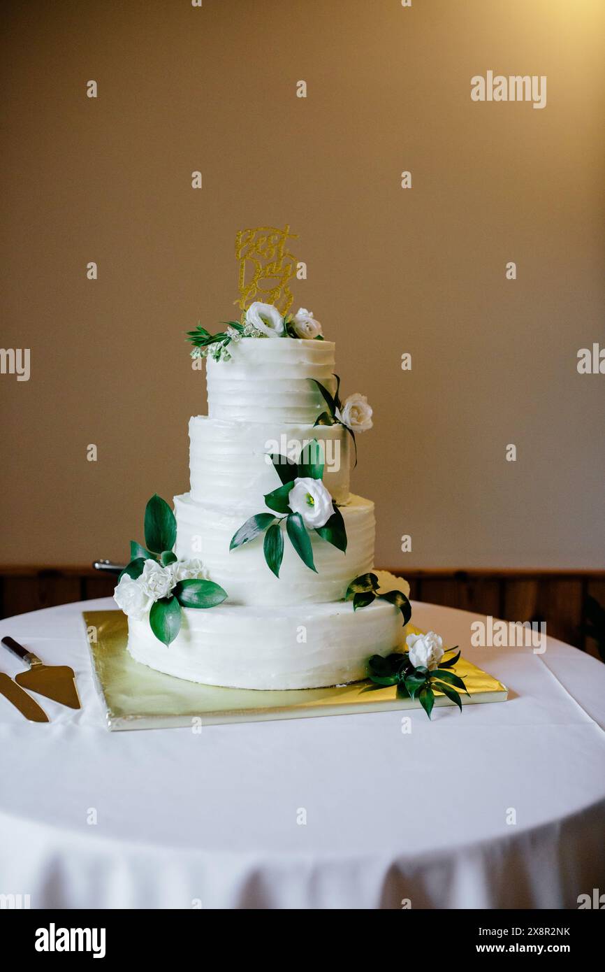 Three-tiered white wedding cake with green leaves, white flowers Stock ...