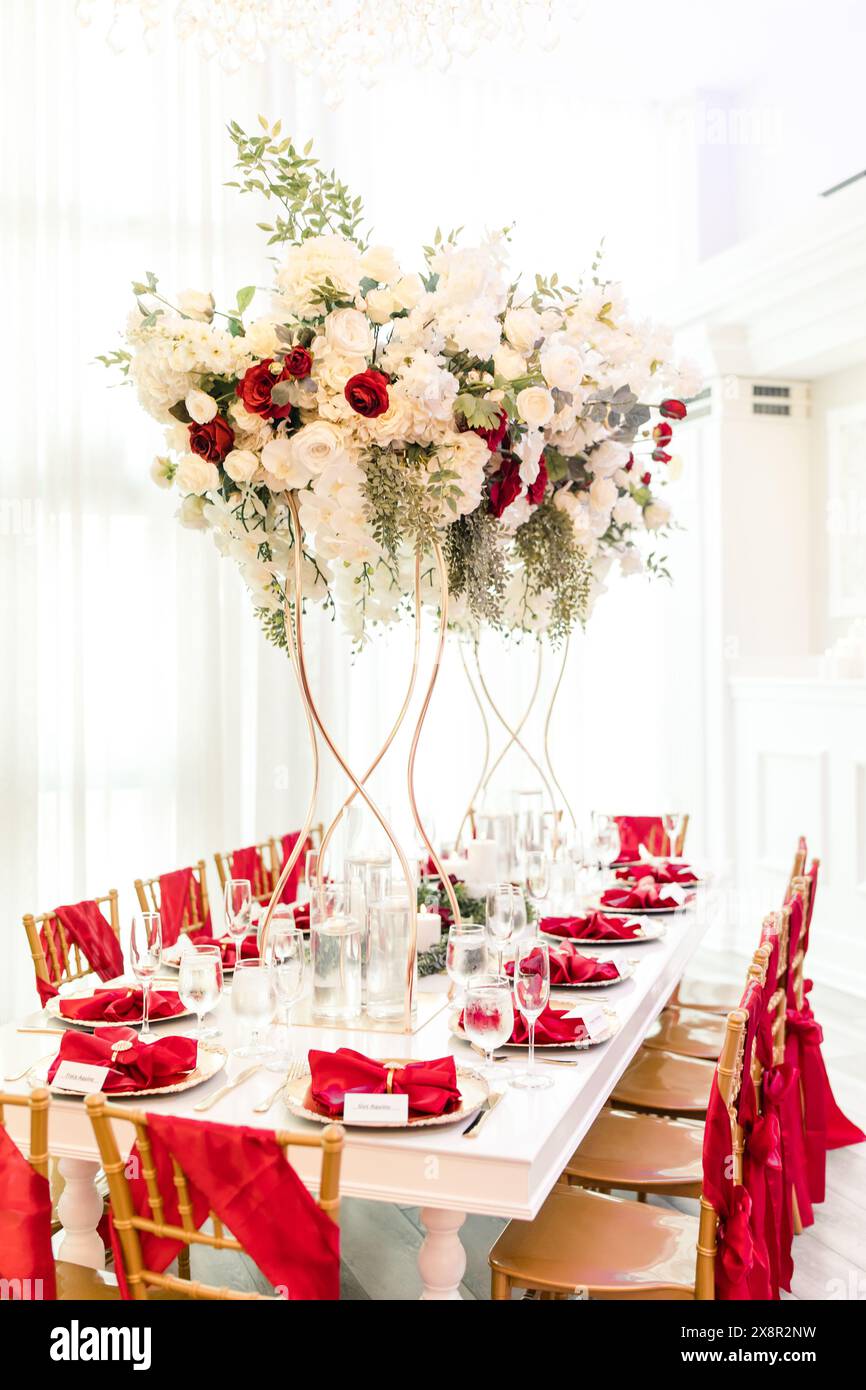 Wedding reception table with tall floral centerpieces and red decor ...