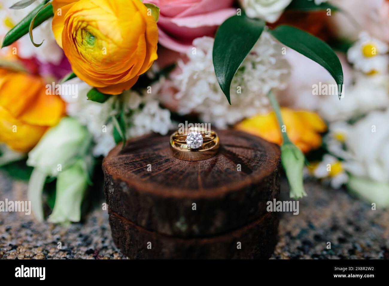 Wedding rings on rustic wood amid vibrant floral bouquet Stock Photo ...