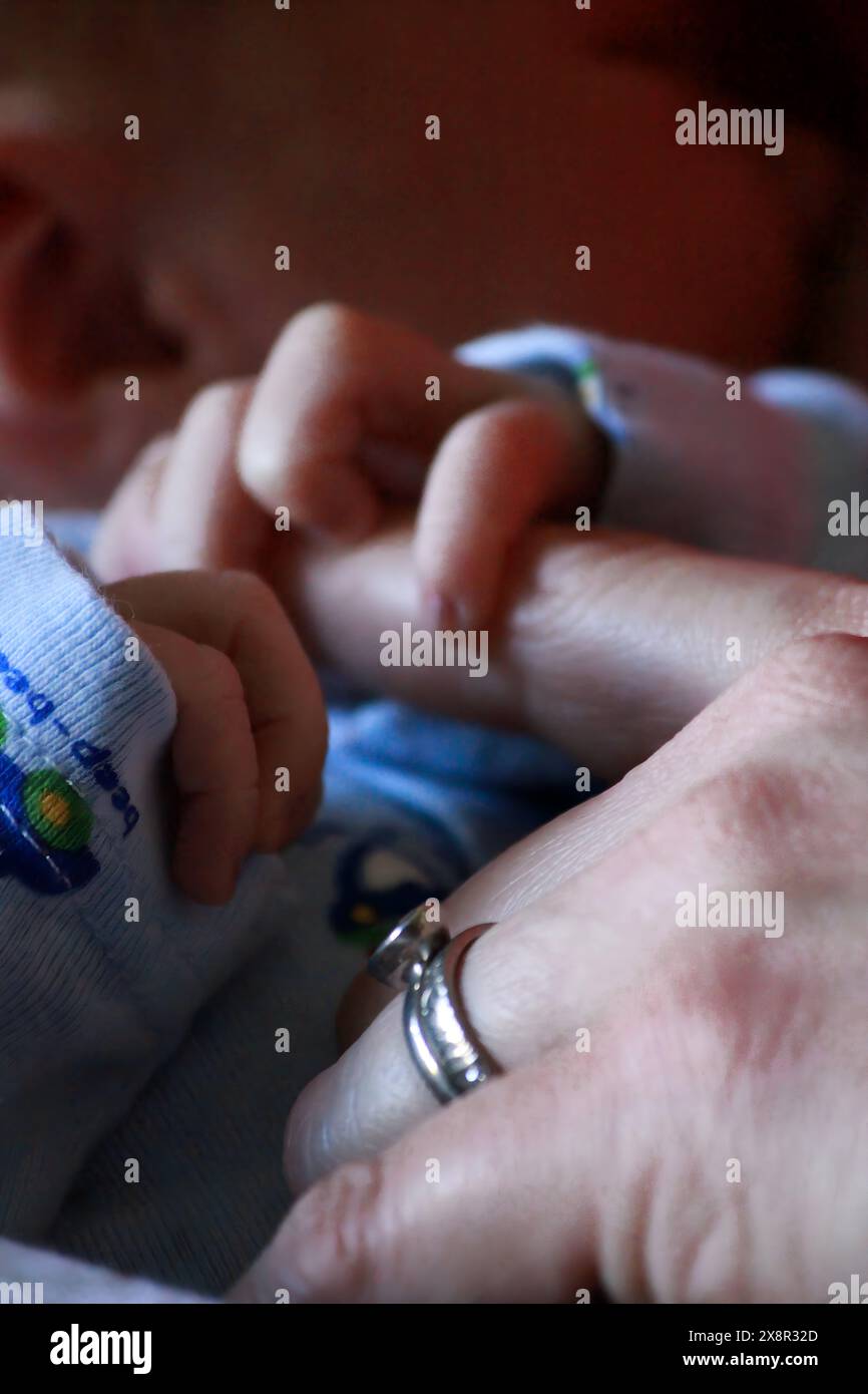 Tiny newborn's hand gently grasps mother's finger Stock Photo - Alamy