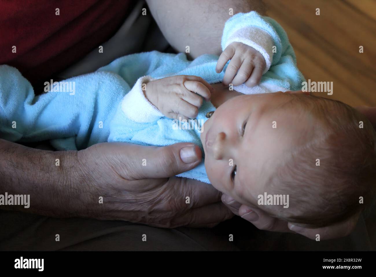 Close-up of grandfather holding newborn baby, sharing a tender moment ...