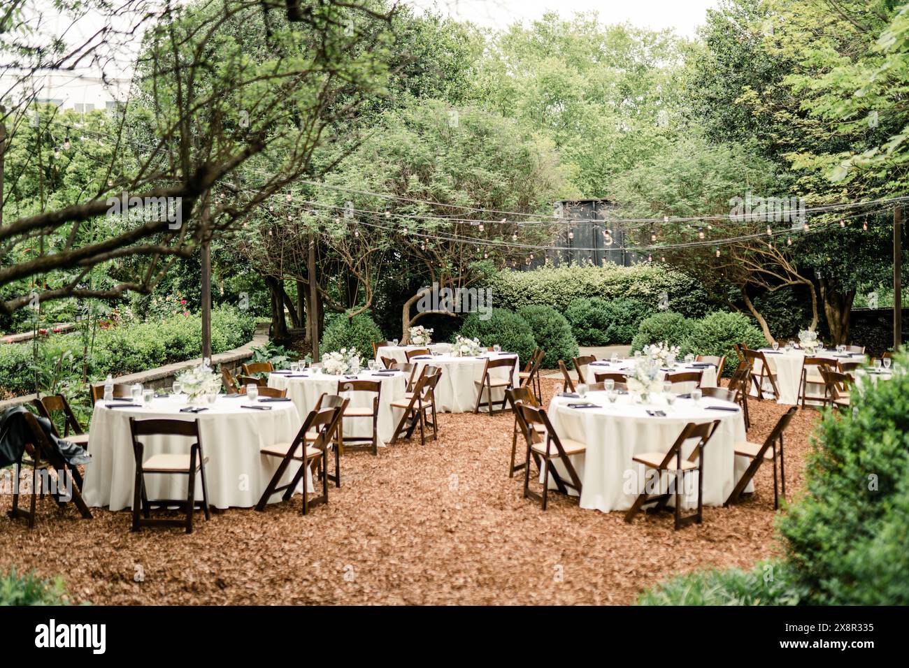 Outdoor garden reception with tables, chairs, and string lights Stock ...