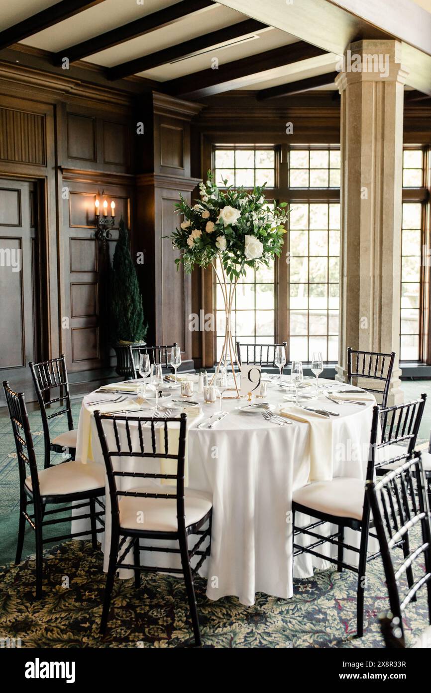 Indoor table setting with tall floral centerpiece and black chairs ...