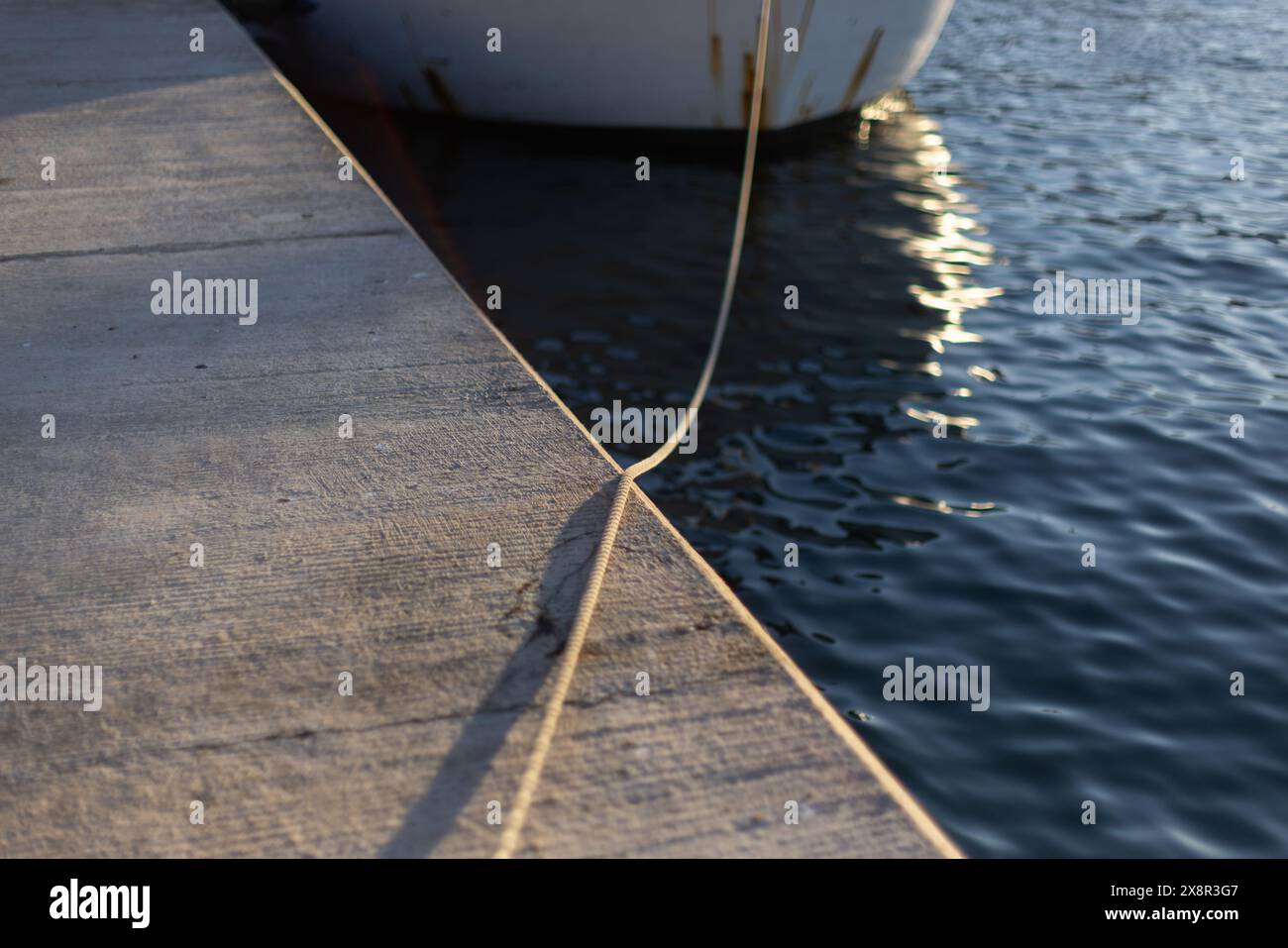 Docked boat tied with a rope, casting a shadow on the pier Stock Photo ...