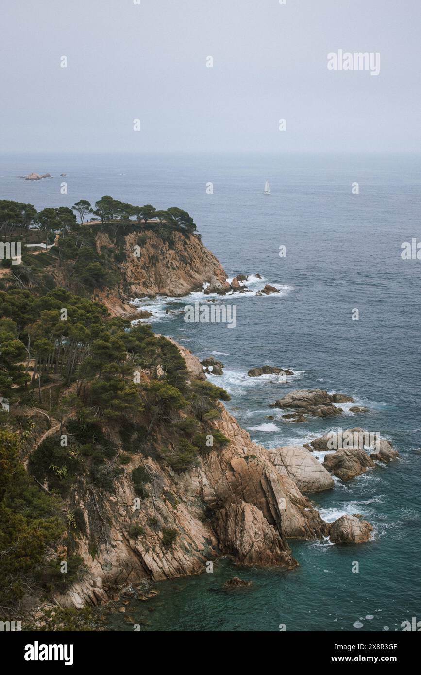 Sailboat by the rocky cliffs of Costa Brava Stock Photo - Alamy