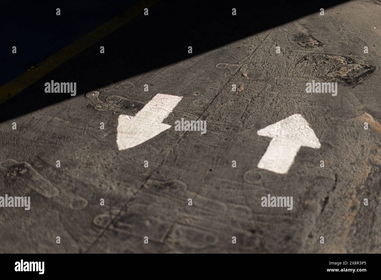 Two white directional arrows on a concrete floor Stock Photo - Alamy