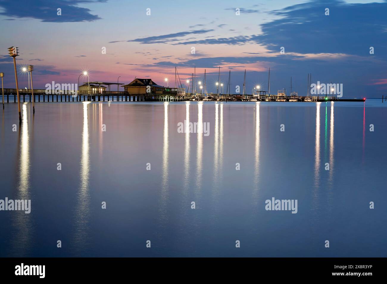 Evening view of a lit pier and marina reflecting on calm water Stock ...