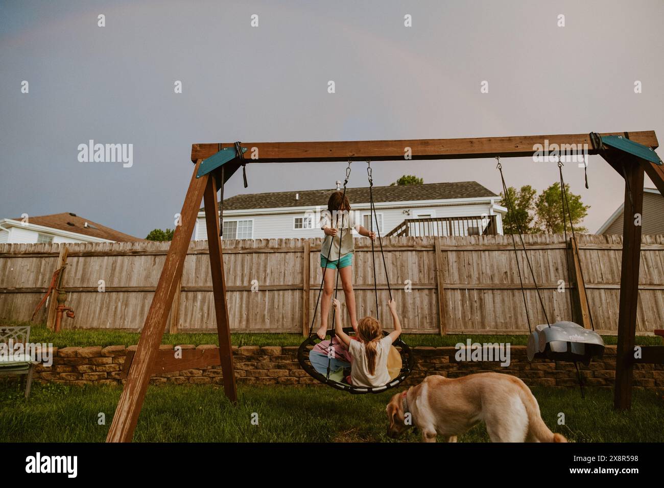 Kids and Dog Playing outside on swing set with Rainbow Stock Photo - Alamy