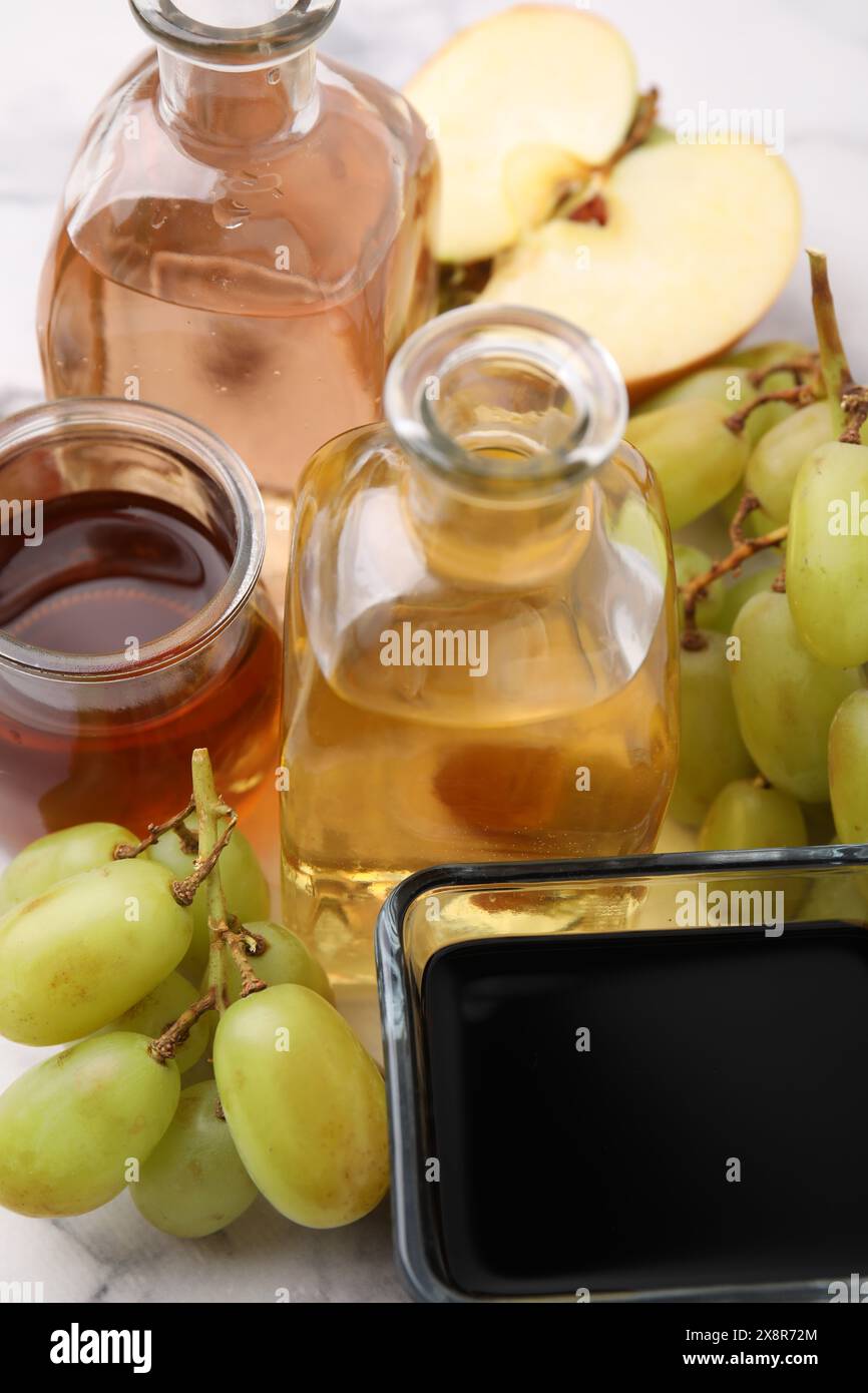 Different types of vinegar and ingredients on light table, closeup ...