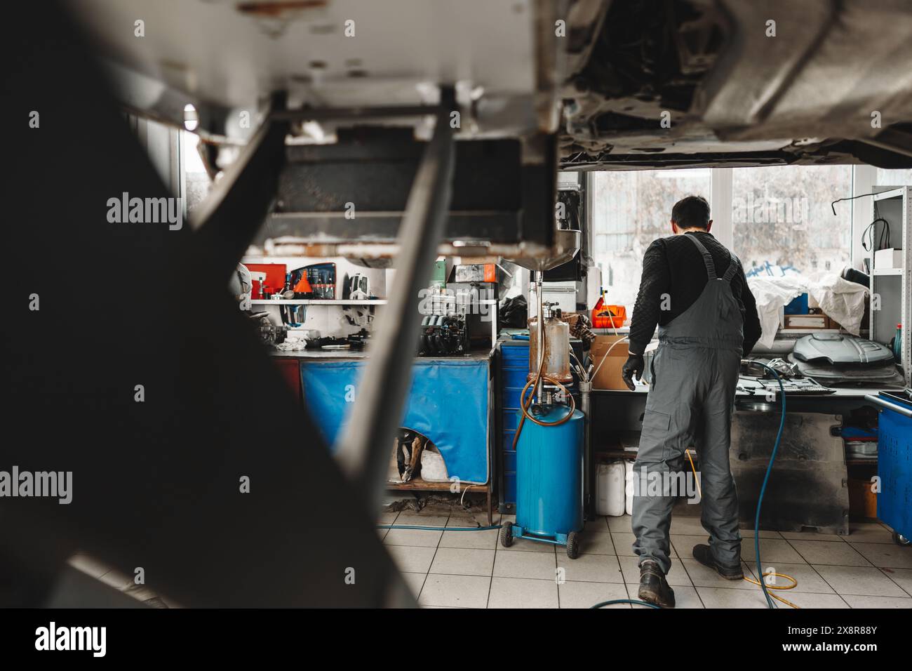 Workman mechanic working under car in auto repair shop Stock Photo - Alamy