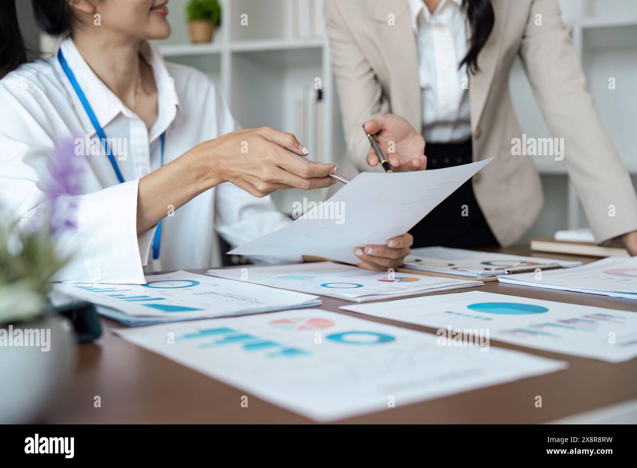 Collaborative business woman meeting hands analyzing financial charts ...