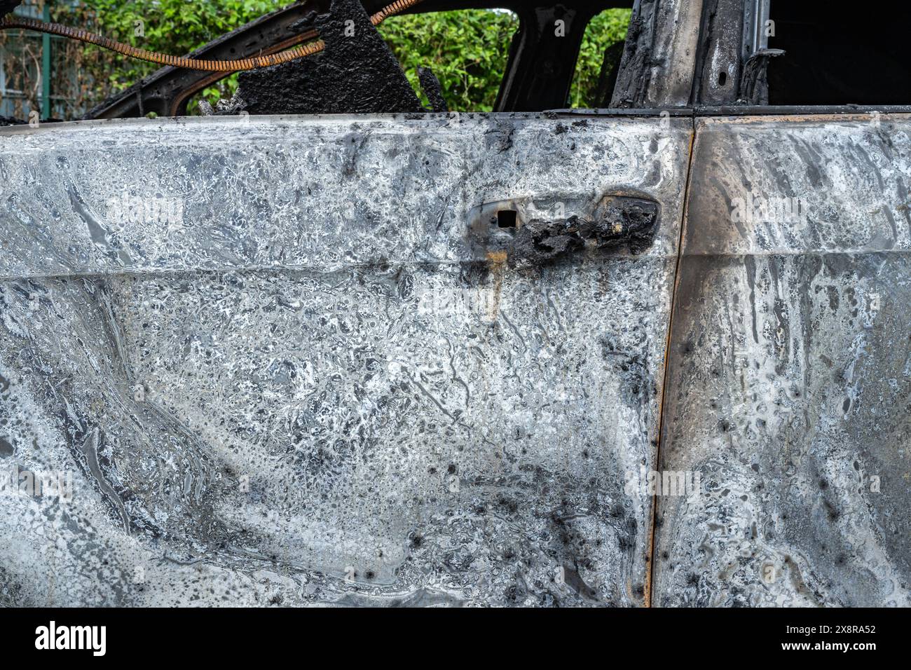 View of a burnt car door with melted door handle and burst, scorched ...