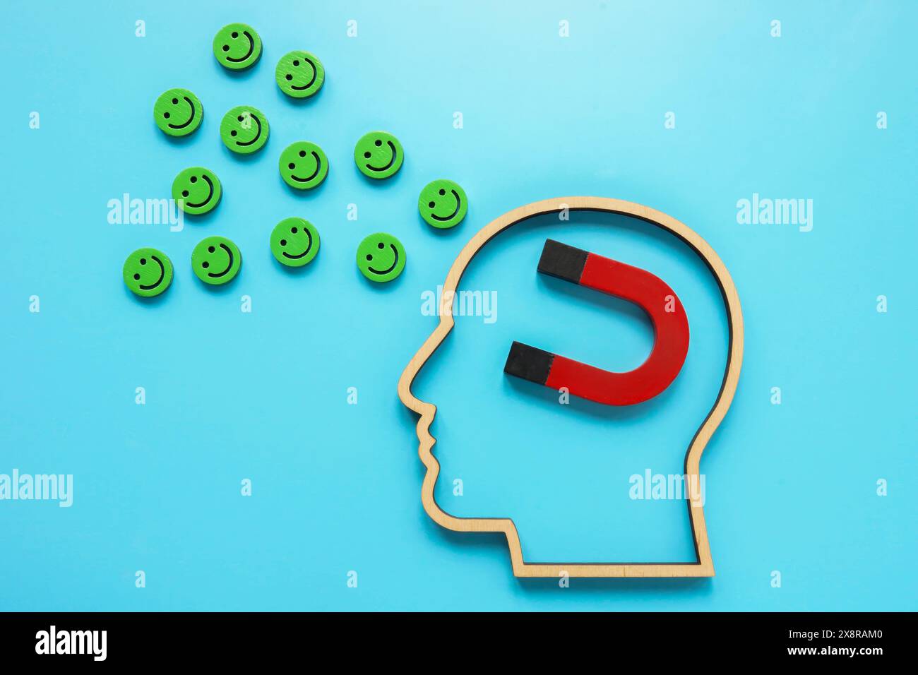 Positive emotions and thinking. A head with a magnet attracts happy ...