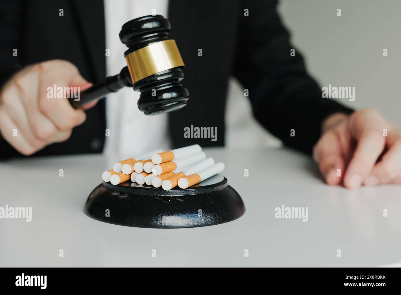Judge hitting cigarettes with referee's gavel on white table. Tobacco ...
