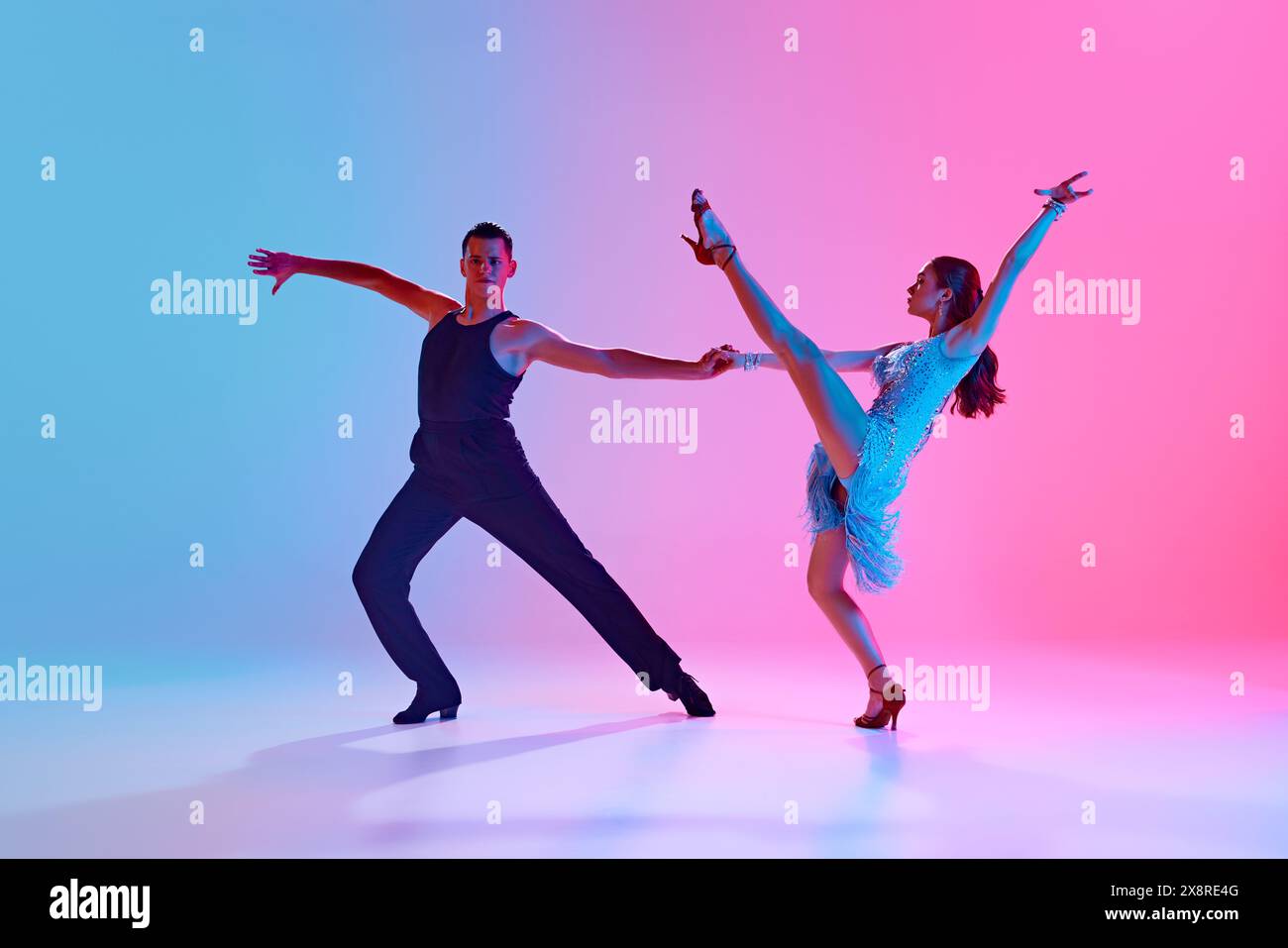 Male and female ballroom dancers captured mid-performance in neon ...