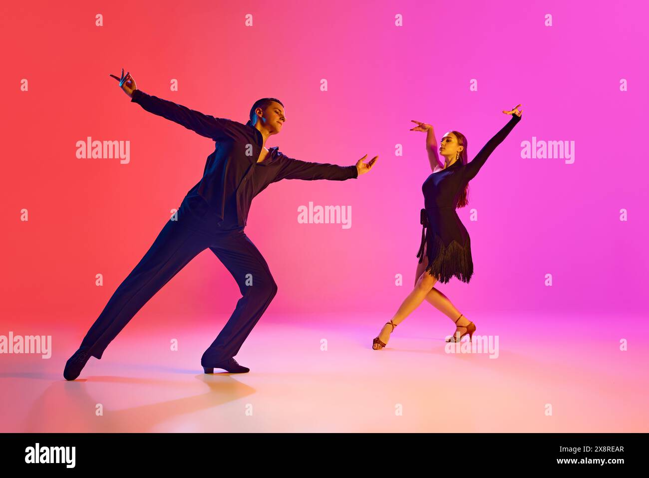 Pair of dancers in elegant poses in neon lighting against gradient ...