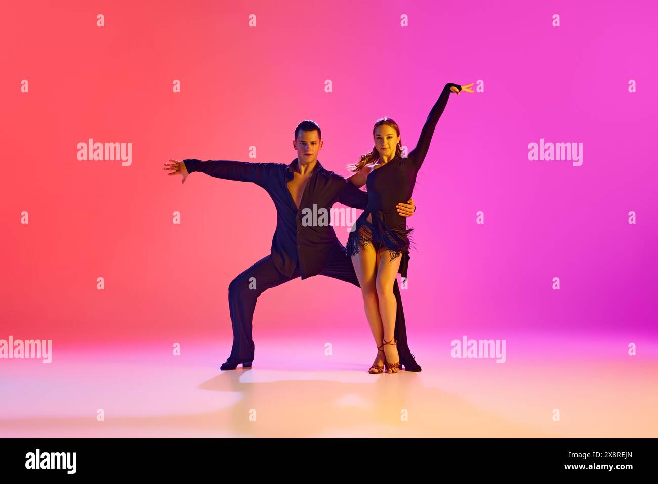 Ballroom dance duo, dressed black stages costumes in action in neon ...