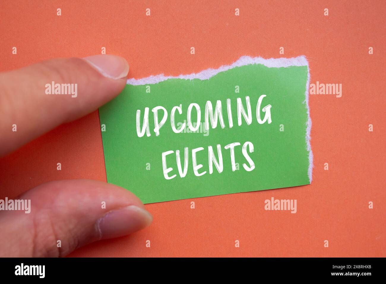 Upcoming events words written on ripped green paper piece with orange background. Conceptual ...