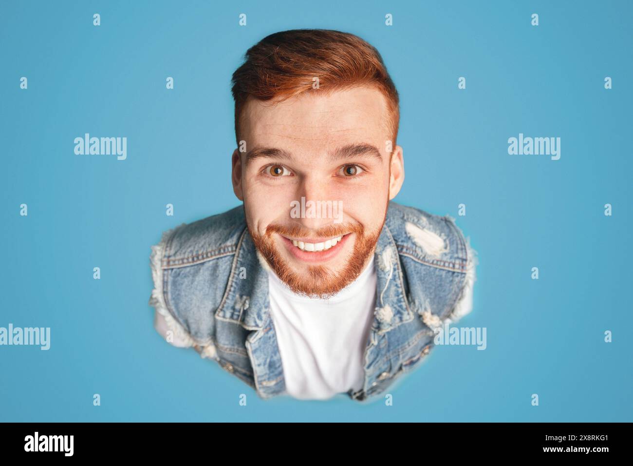 Above portrait of funny millennial redhaired guy, smiling at camera ...