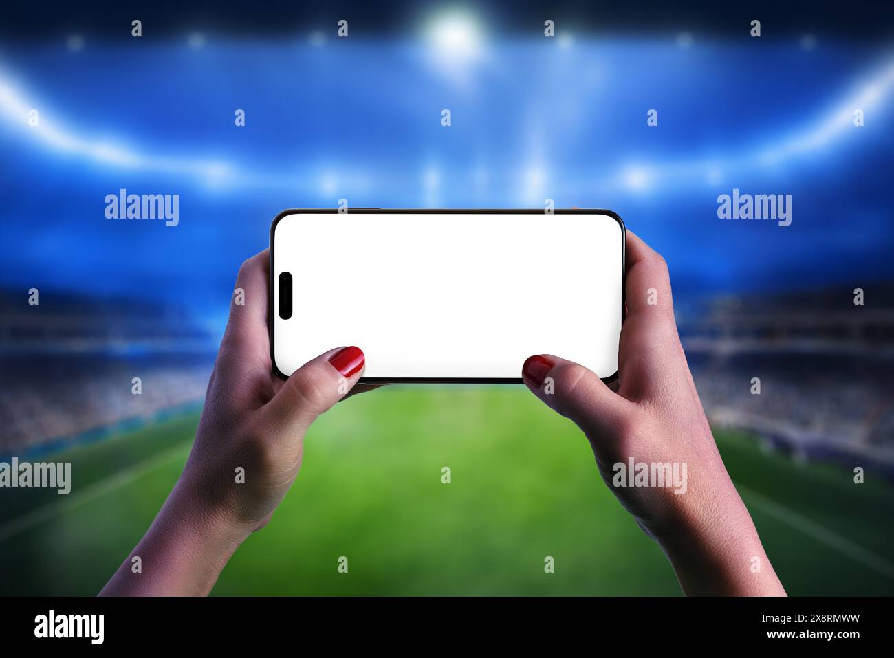 Mobile phone held horizontally in hands at a football stadium, perfect ...