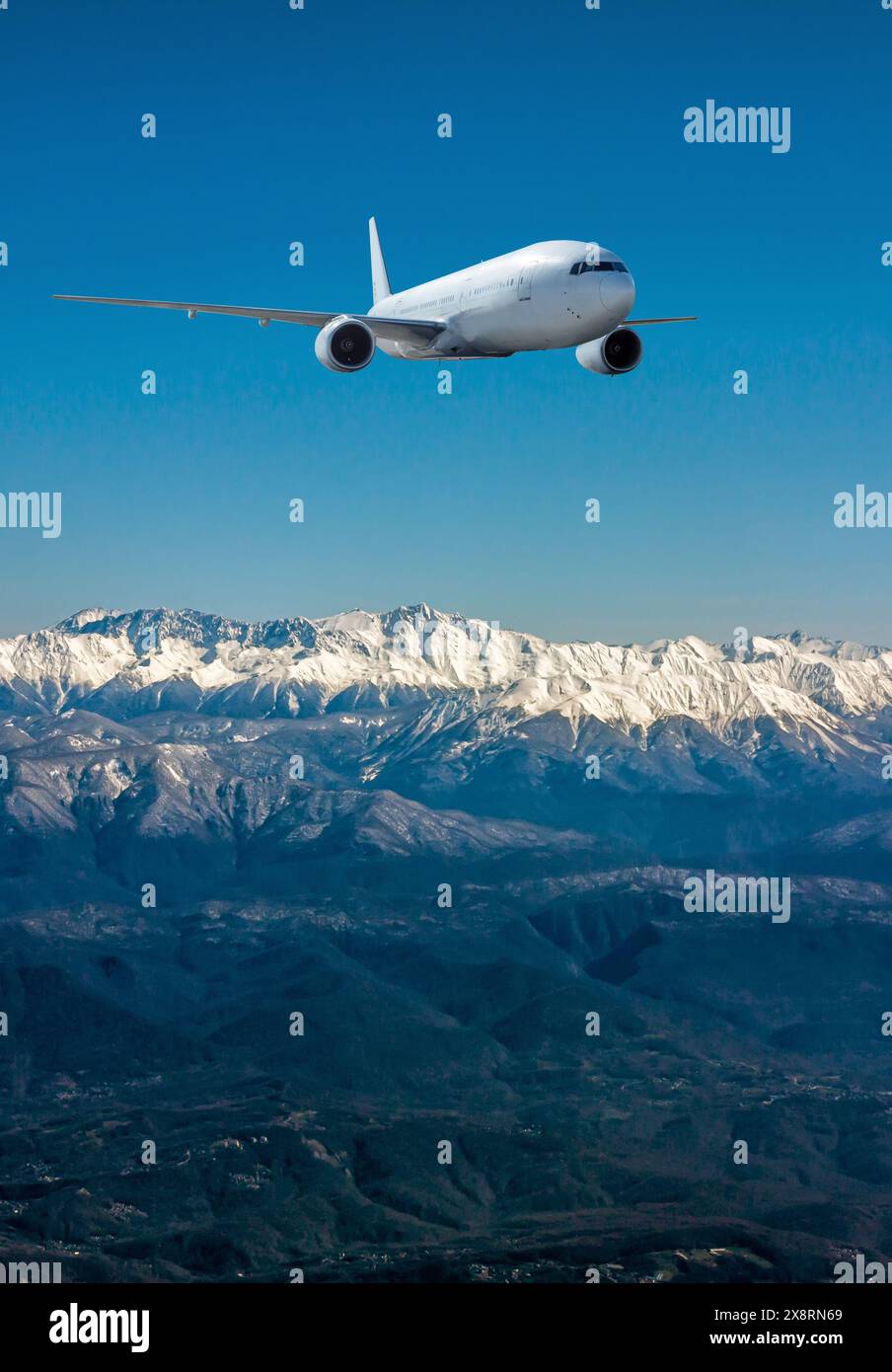 A white wide body jet plane flies over resort mountain town Stock Photo ...