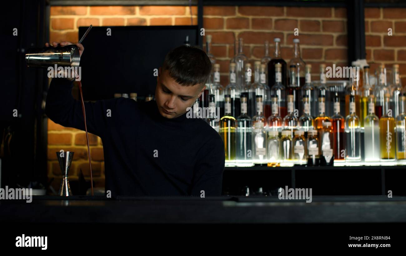 The barman preparing perfect cocktail, standing behind the bar counter ...