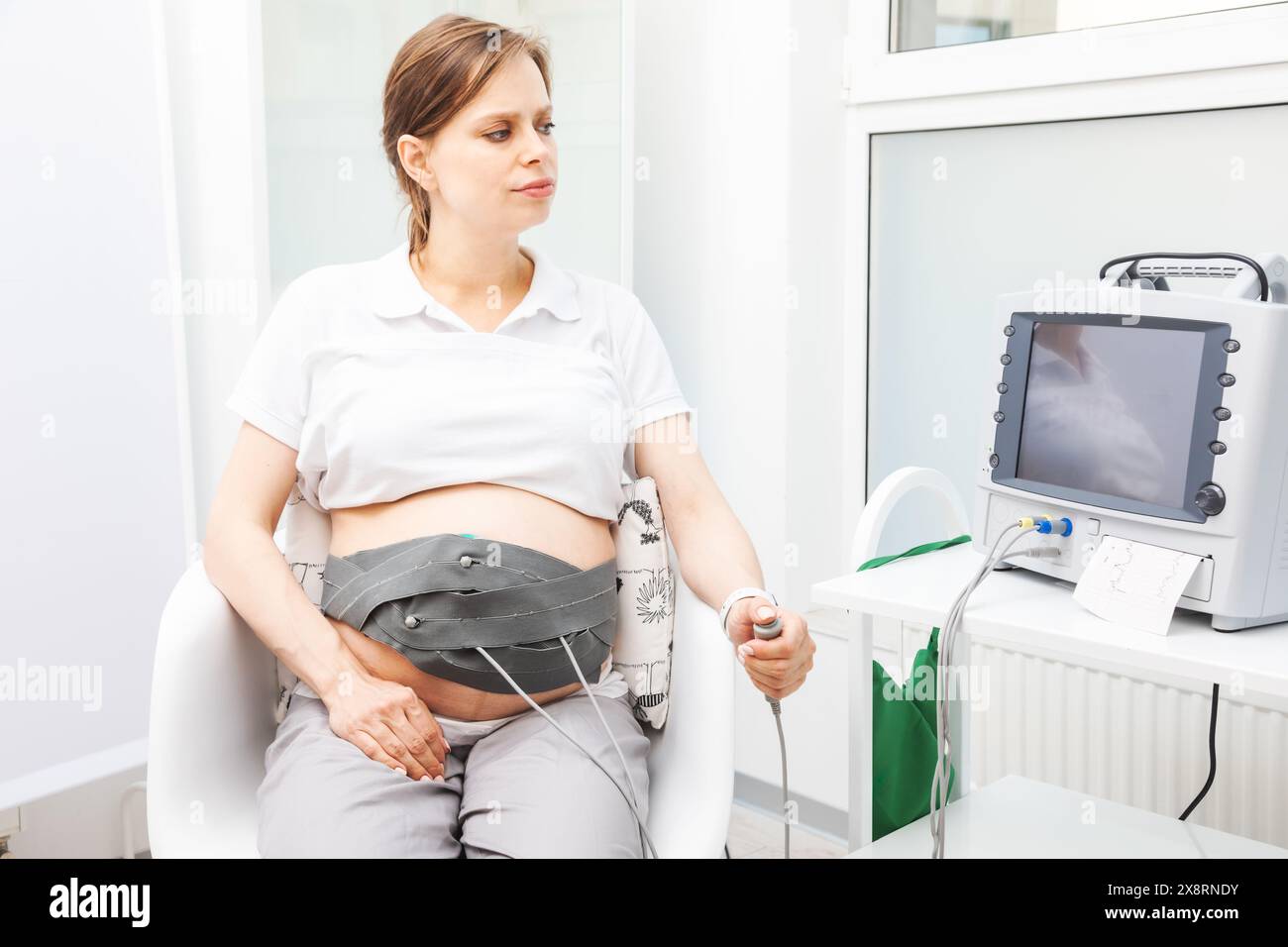 A pregnant woman performing cardiotocography (CTG) to monitor fetal ...