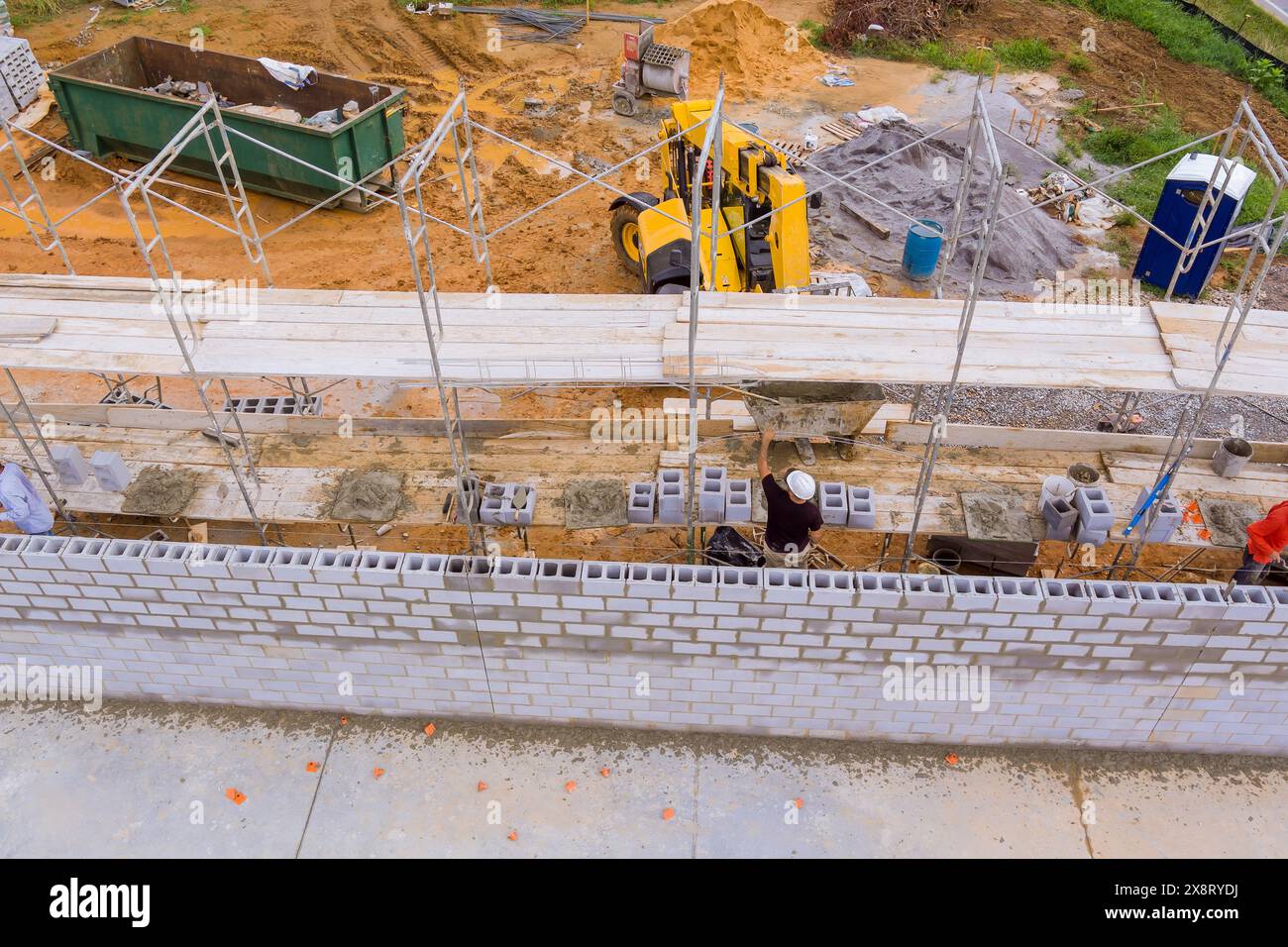 On construction site, mason stands on scaffolding constructs concrete ...