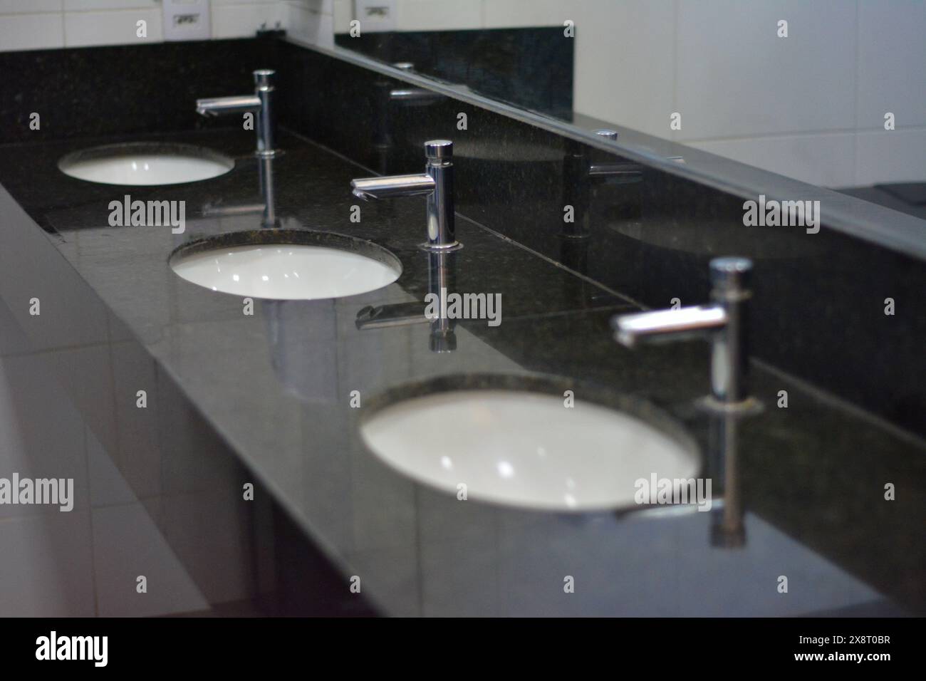 Washbasins in public bathroom with taps in selective focus Stock Photo ...