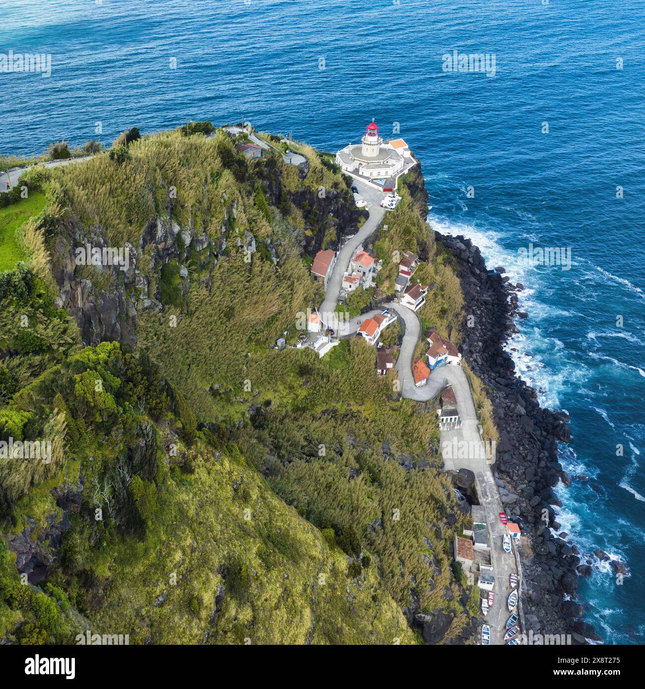 Aerial view of a curvy road leading to a lighthouse in the Azores ...