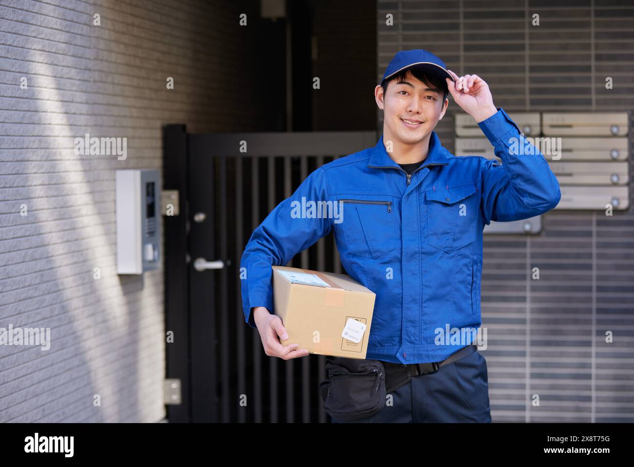 Japanese delivery man holding package and smiling Stock Photo - Alamy